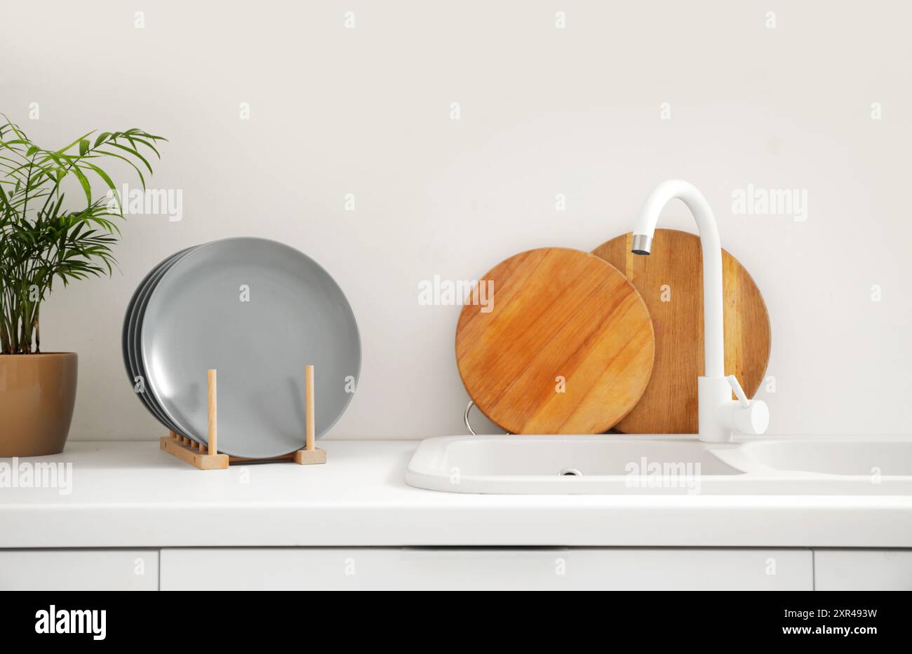 Stack of clean plates near sink on white counter in kitchen Stock Photo ...