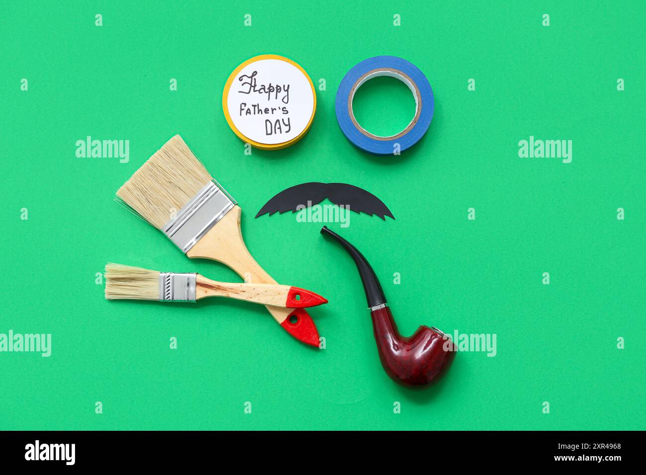 Adhesive tape, paint brushes, smoking pipe and greeting card with text ...