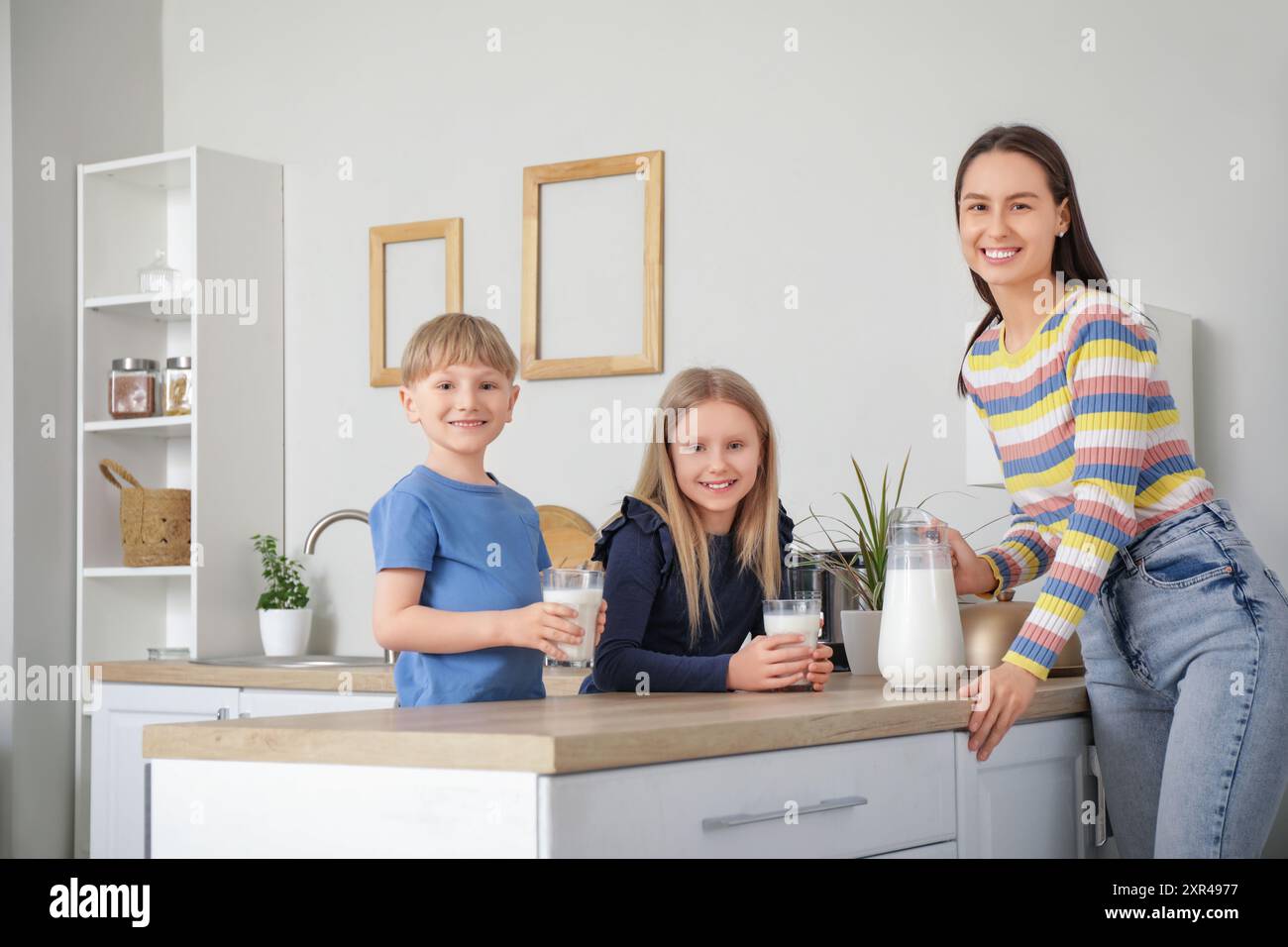 Happy family drinking milk at counter in kitchen Stock Photo - Alamy