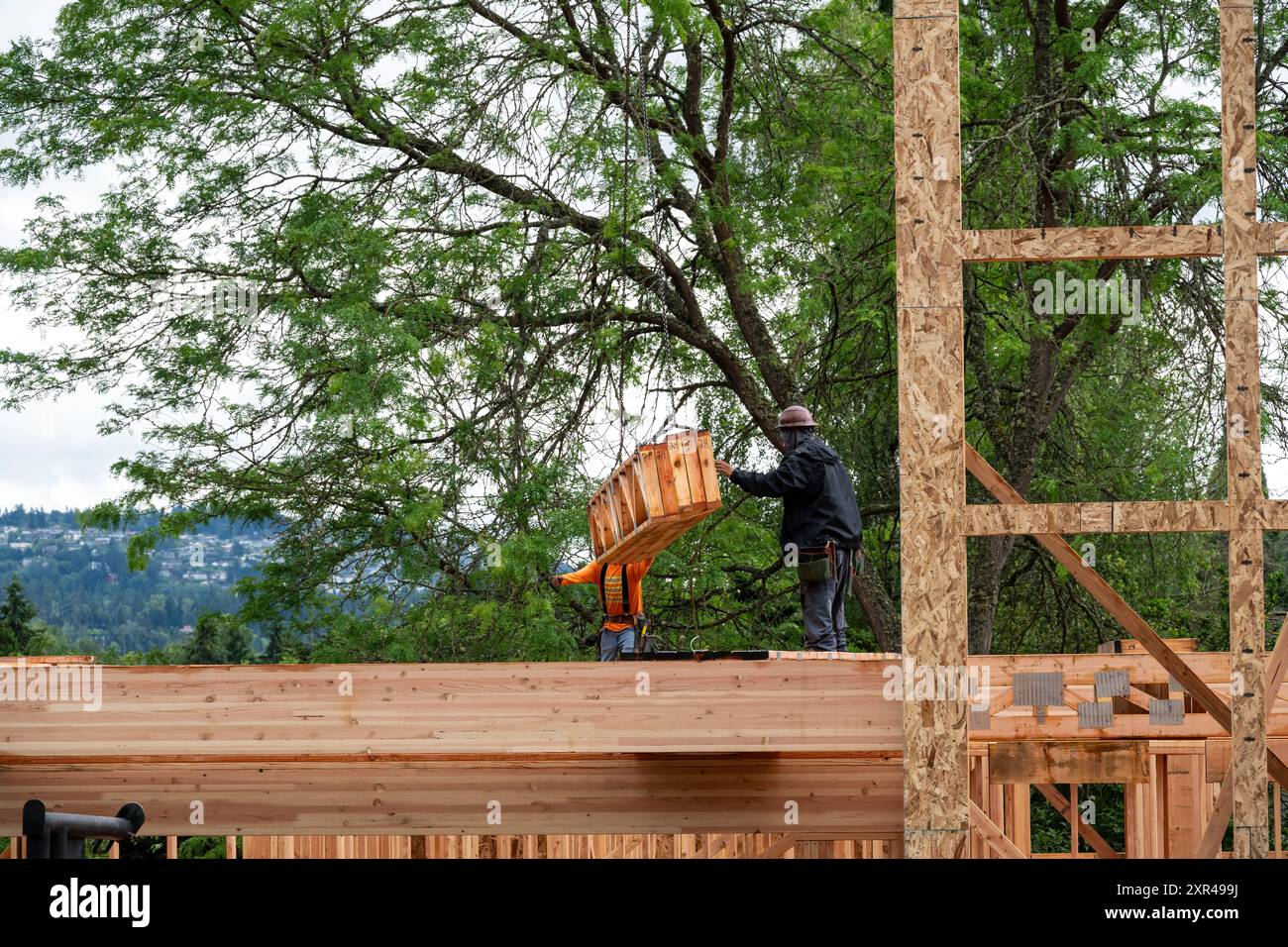 Residential house construction, boom crane lifting lumber delivery ...