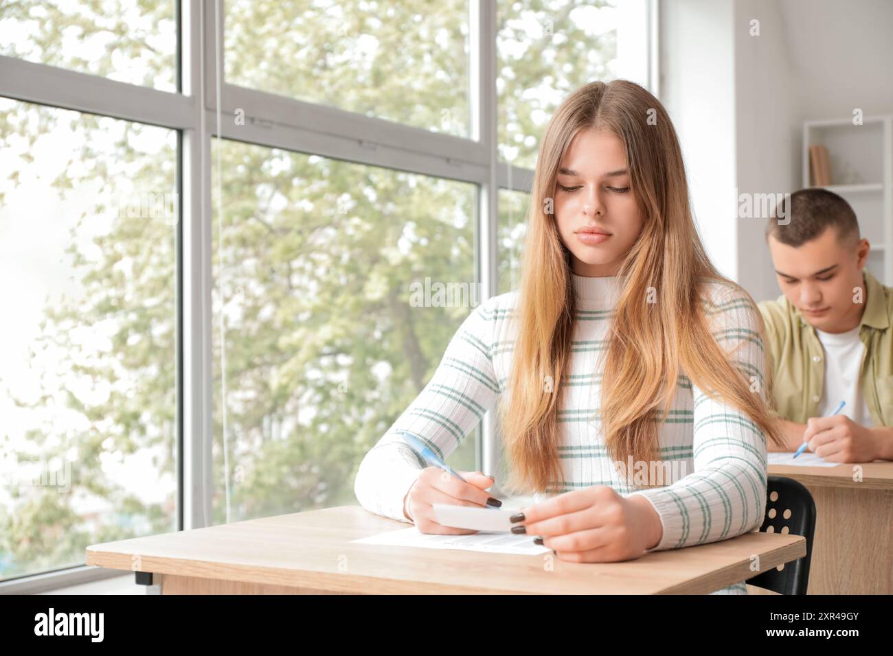 Female student passing exam at desk in classroom Stock Photo - Alamy