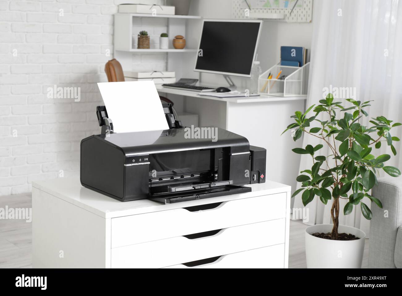 Modern printer on chest of drawers and workplace in stylish office ...