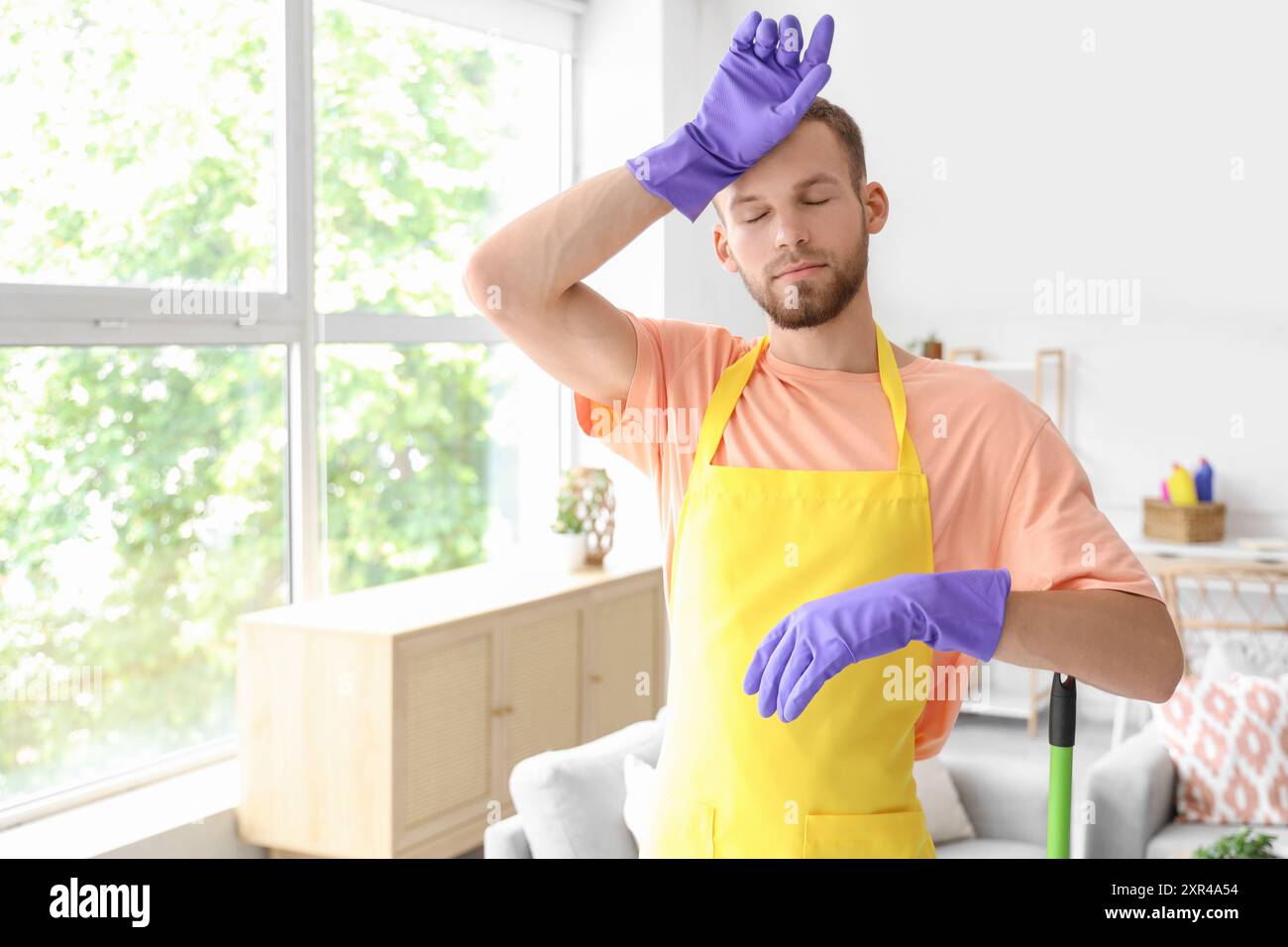 Tired male janitor in rubber gloves in light room Stock Photo - Alamy