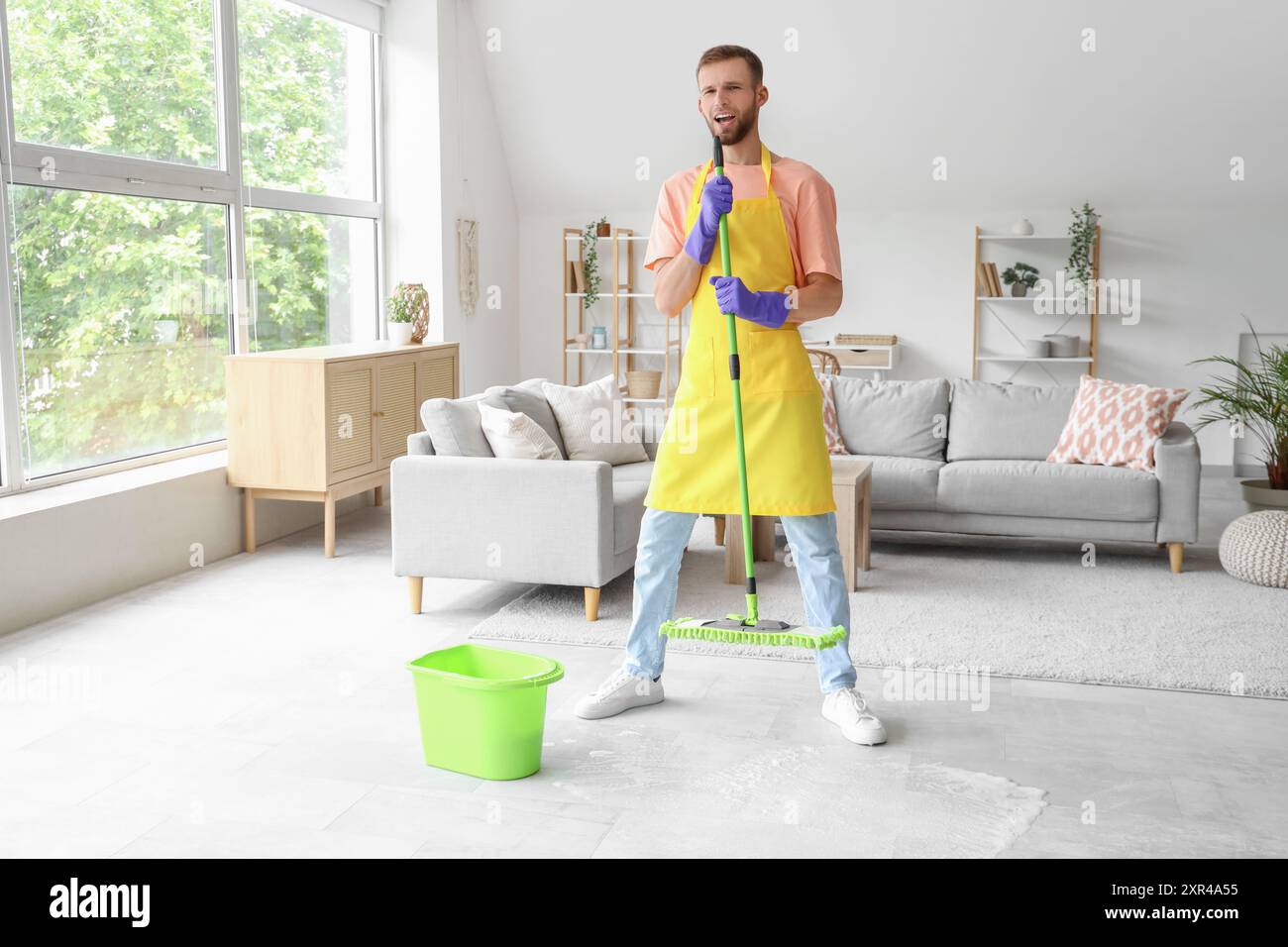 Male janitor cleaning floor with mop and singing in room Stock Photo ...