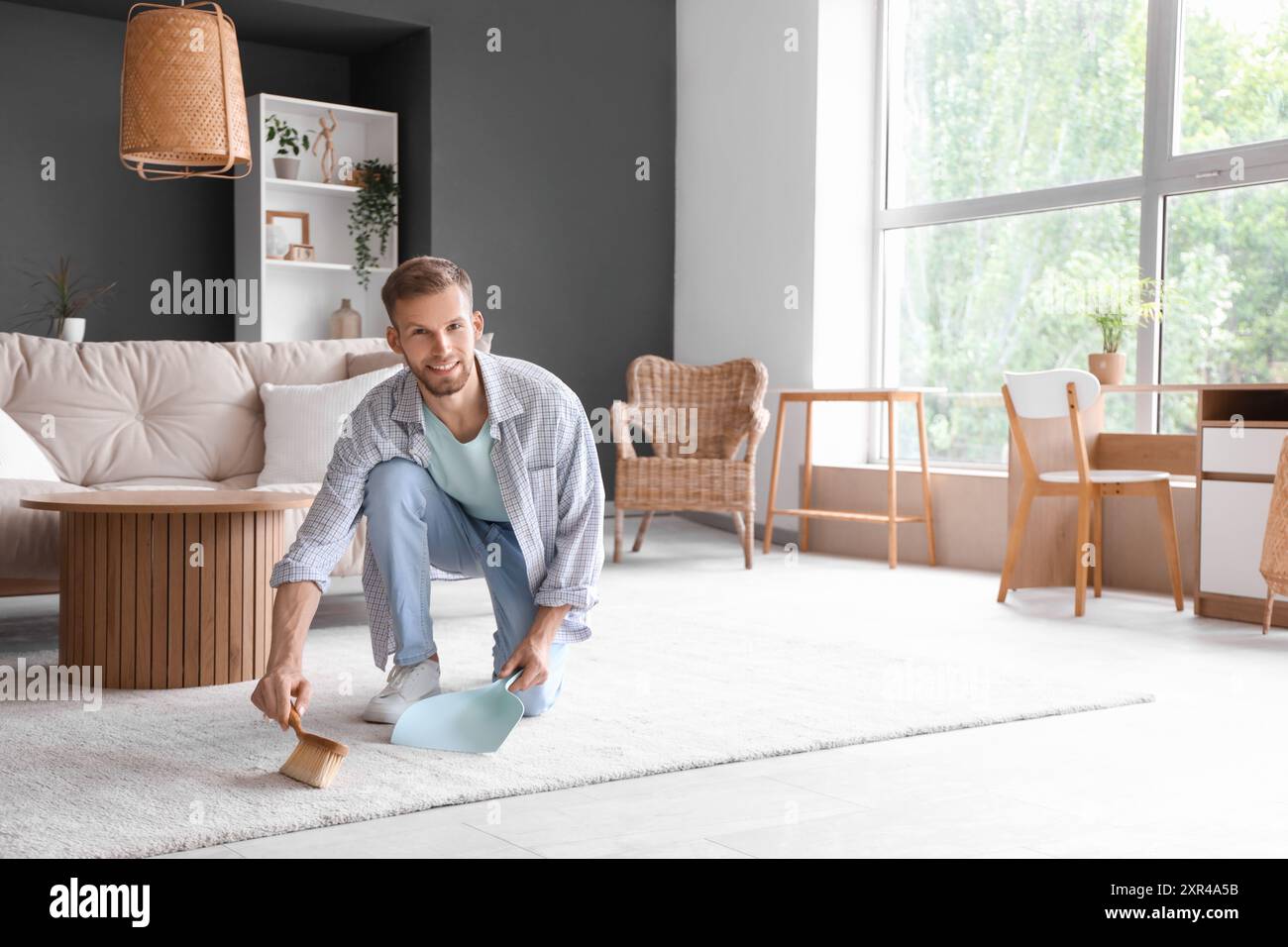 Male janitor with dust pan and brush cleaning floor in light room Stock ...