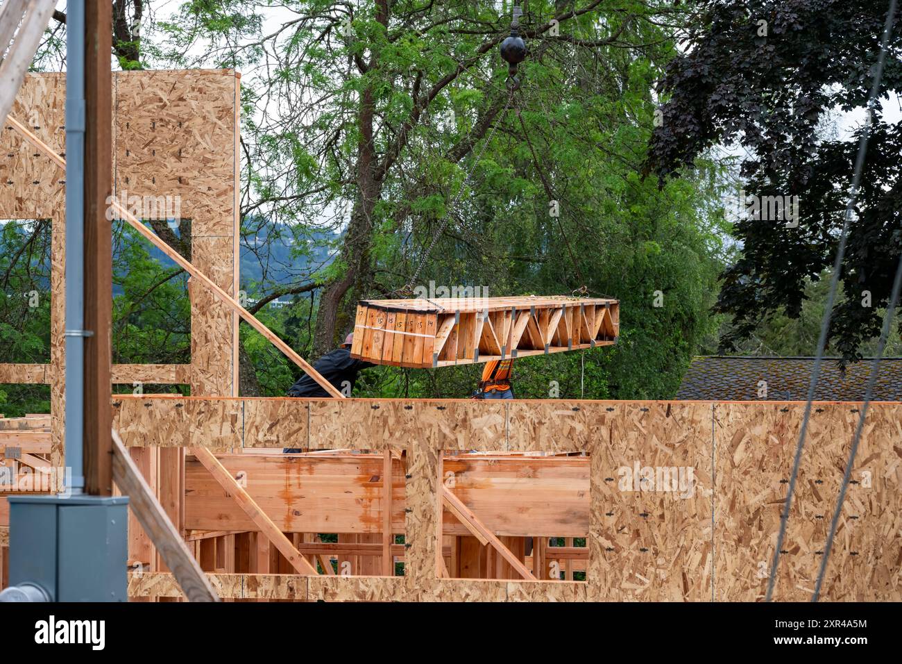 Residential house construction, boom crane lifting lumber delivery ...