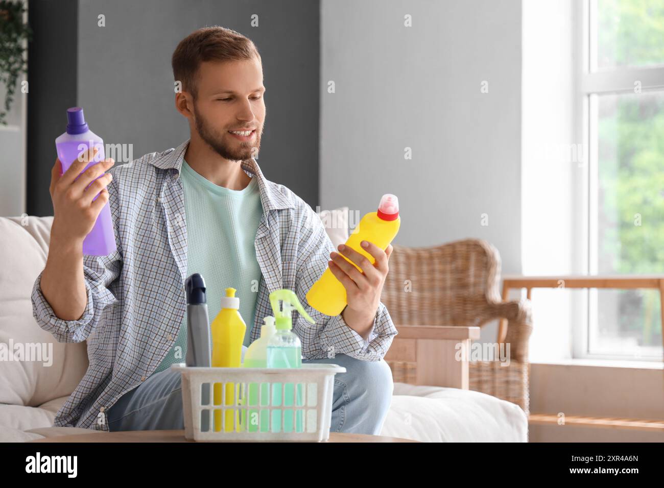 Male janitor and basket of cleaning supplies on coffee table in room ...