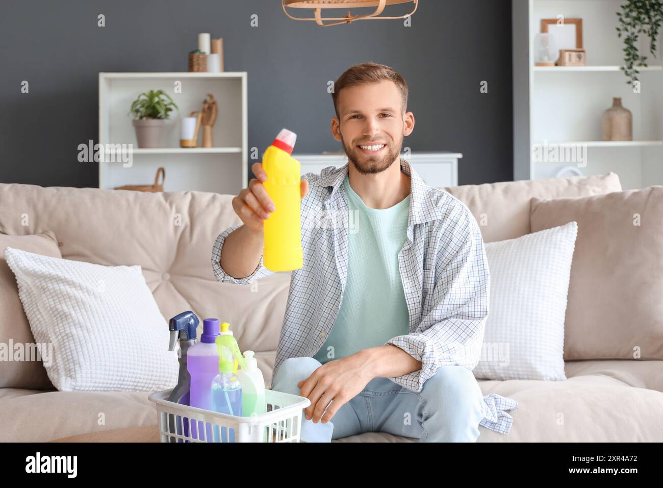 Male janitor and basket of cleaning supplies on coffee table in room ...