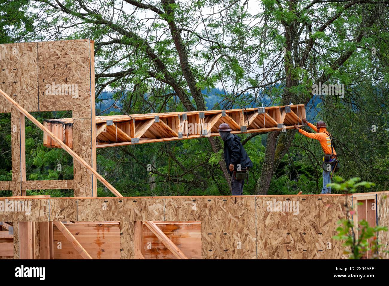Residential house construction, boom crane lifting lumber delivery ...