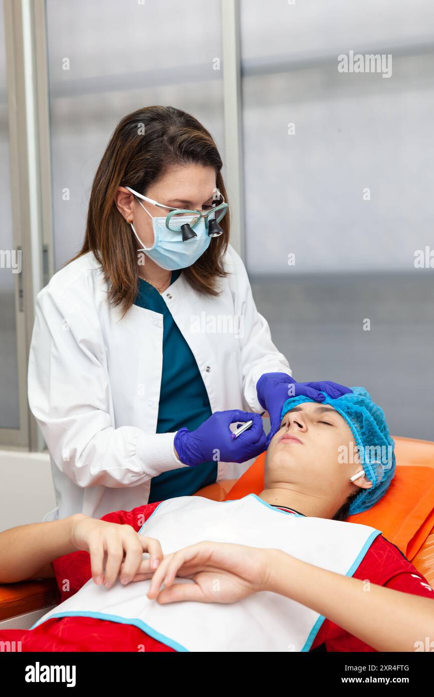 Skin lesion removal procedure. Dermatologist carrying out a removal of ...