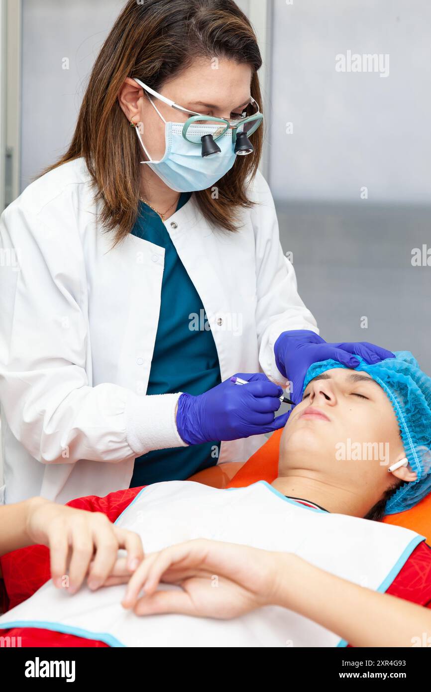 Skin lesion removal procedure. Dermatologist carrying out a removal of ...