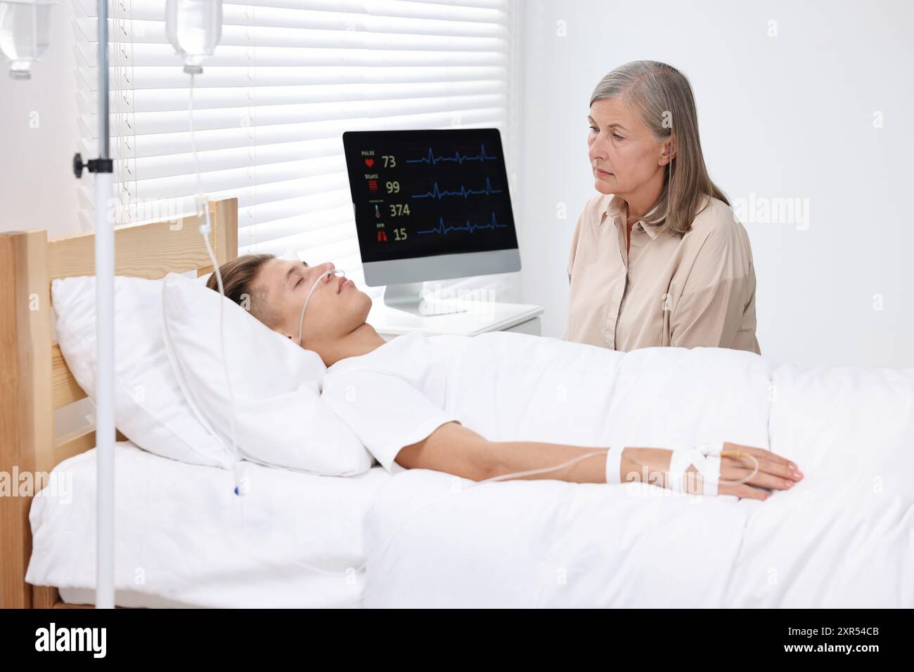 Coma patient. Sad mature woman near her unconscious son in hospital ...