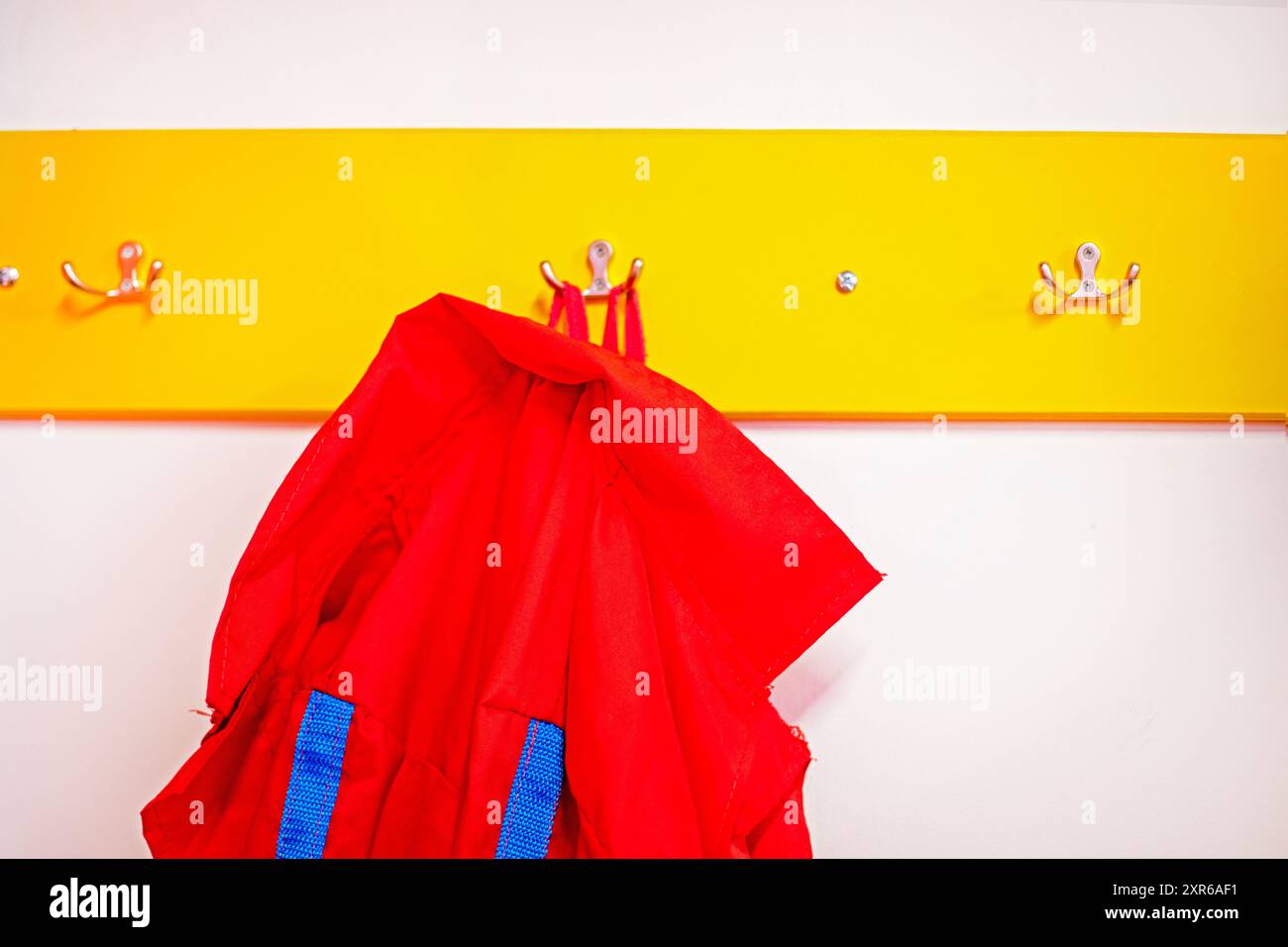 red work clothes on a yellow hanger in the interior Stock Photo - Alamy