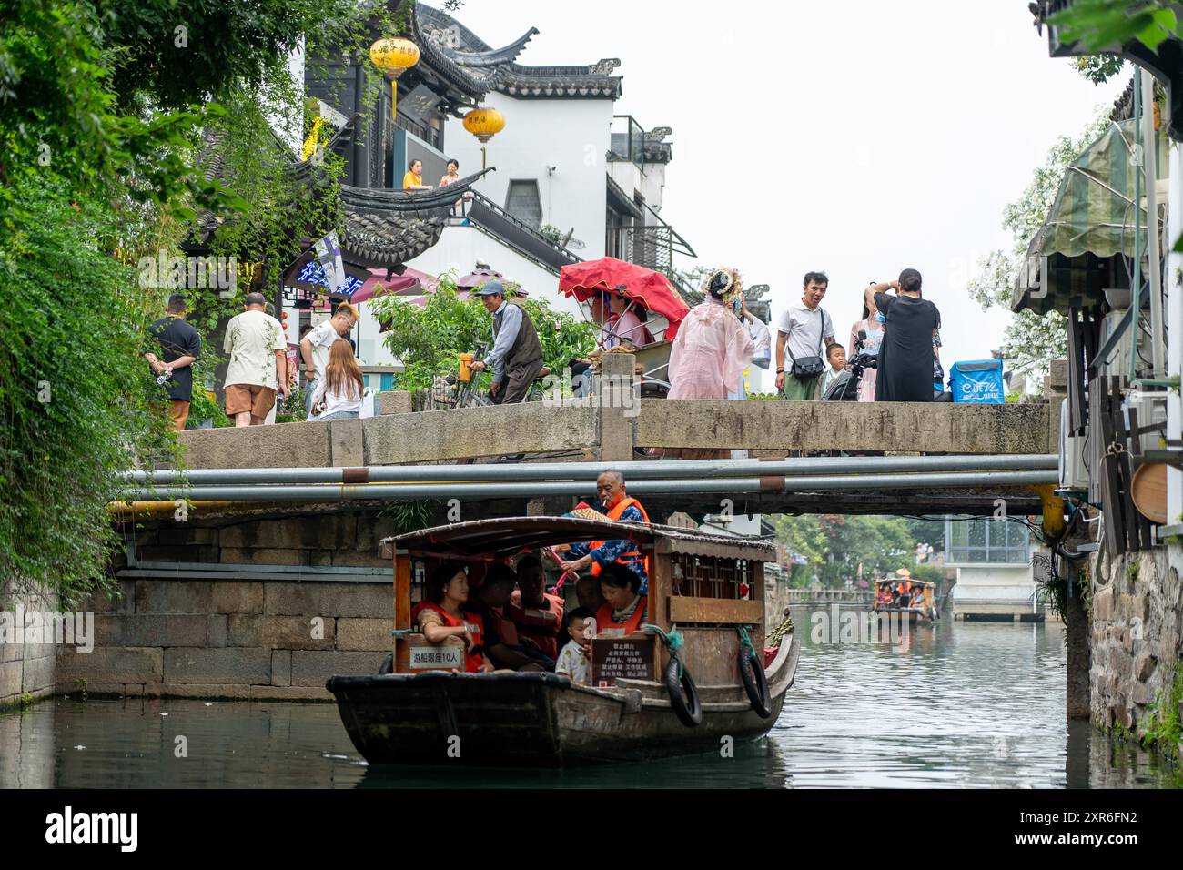 Suzhou, China - June 11, 2024 : A boat full of people navigates a canal ...
