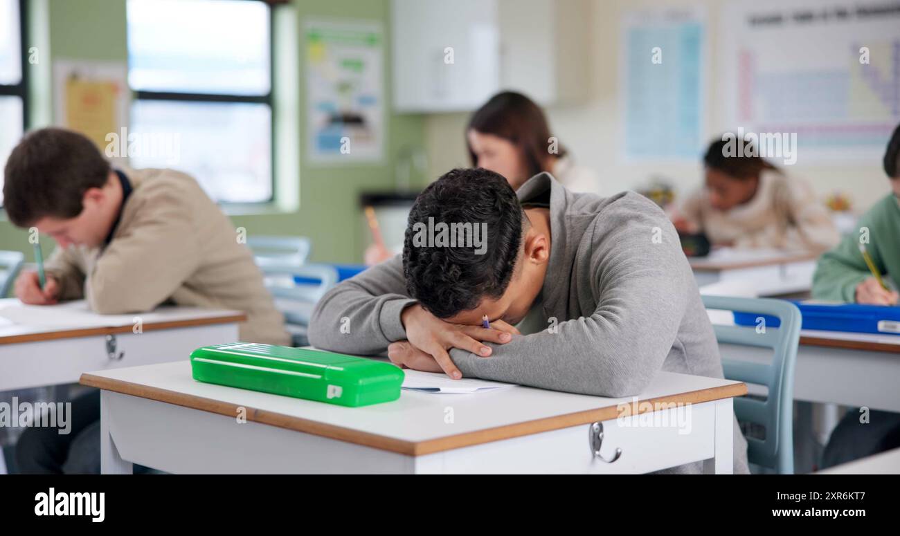 Exam, boy and tired on desk with stress, overwhelmed and brain fog in ...
