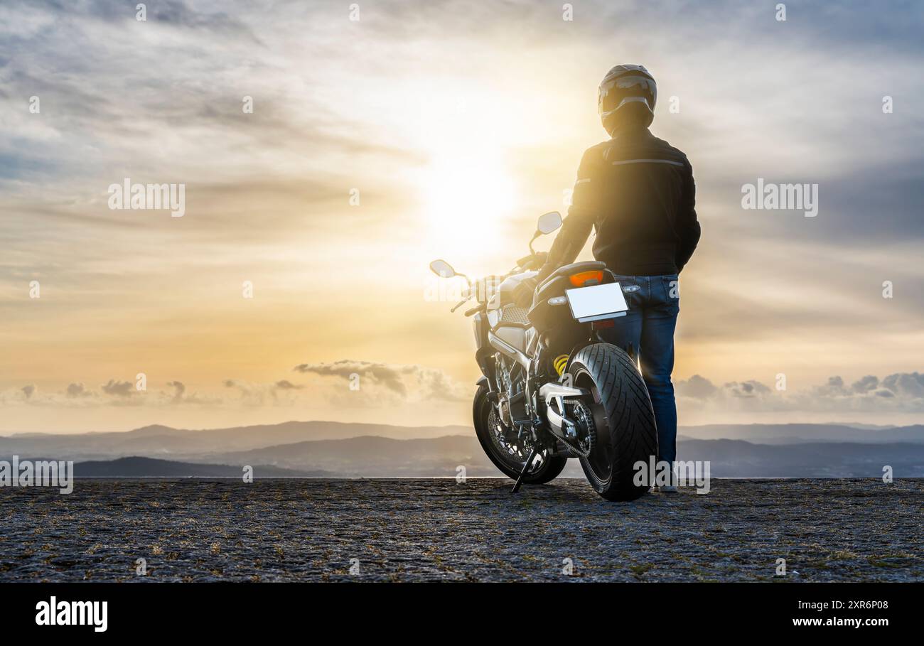 biker standing next to the motorcycle, watching the sunset - copy space ...