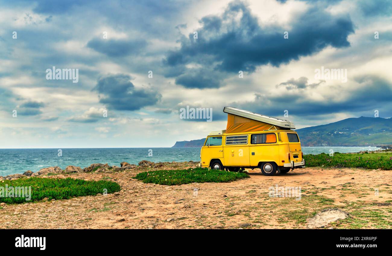 yellow camper van standing in front of the sea on a cliff with dramatic ...