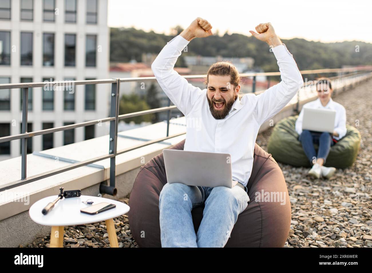 Happy man celebrating with laptop on rooftop while working Stock Photo ...
