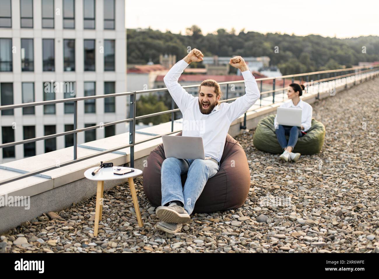 Excited man working on laptop outdoors on rooftop with colleague Stock ...