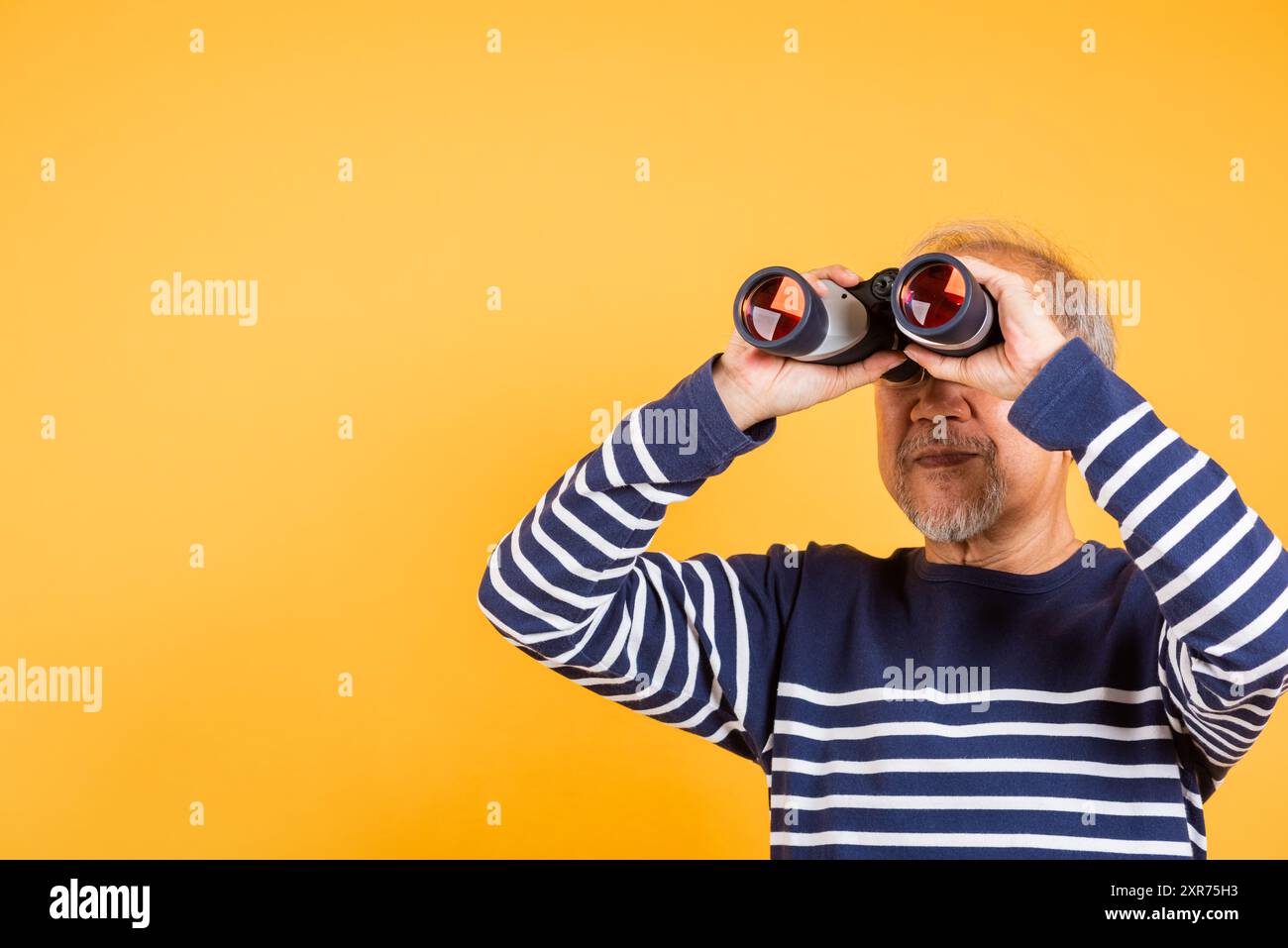 Portrait Asian smiling old man looking camera through binoculars studio ...
