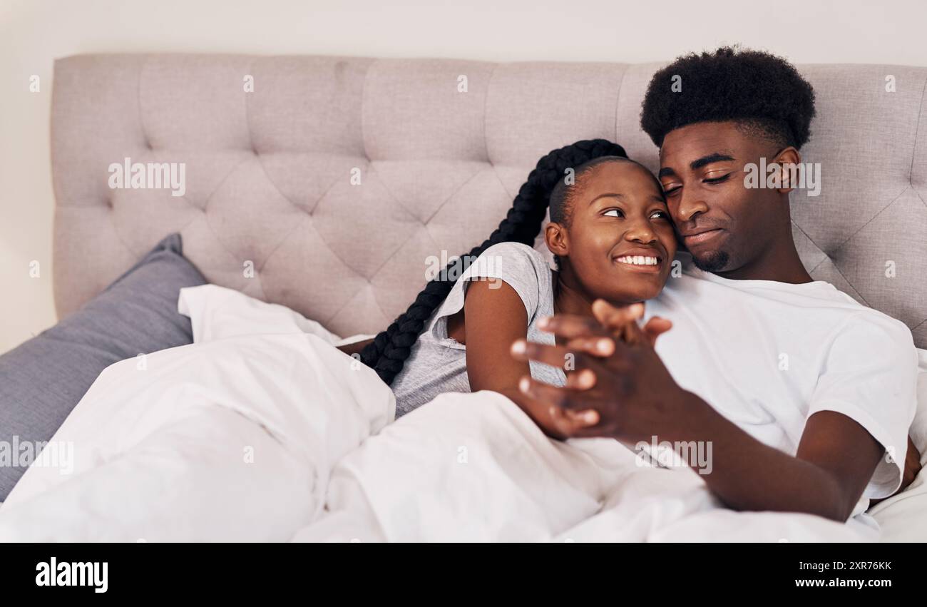 Happy, black couple and relax with love in bedroom of hotel for weekend ...