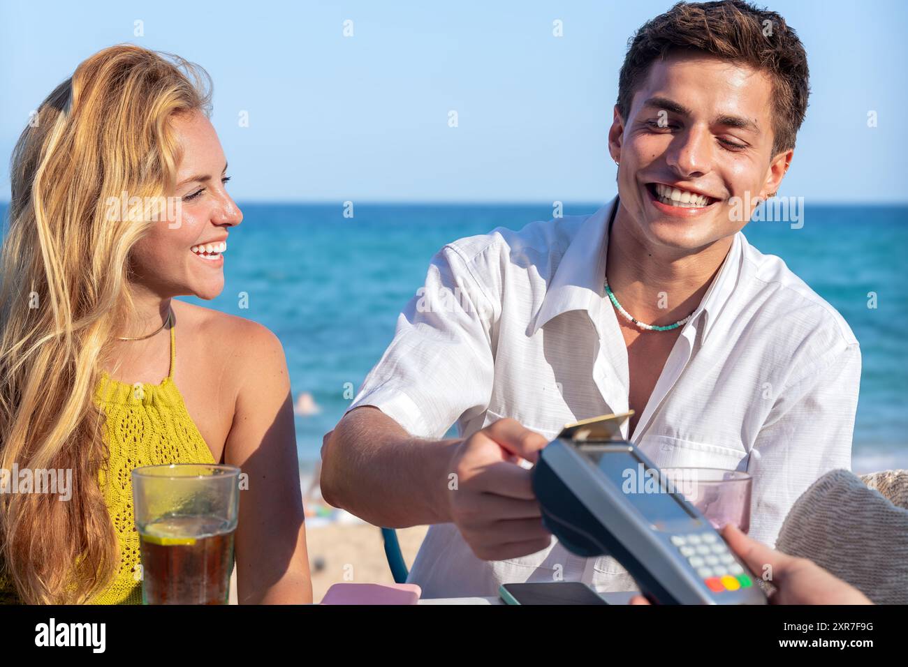 Smiling friends customer paying with contactless credit card in a ...