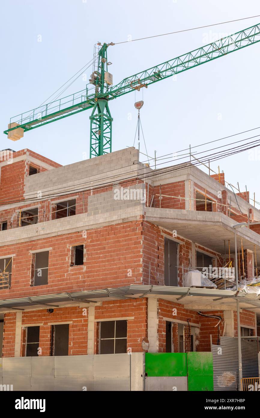 Vivid capture of construction site showcasing building in progress with brickwork and crane ...