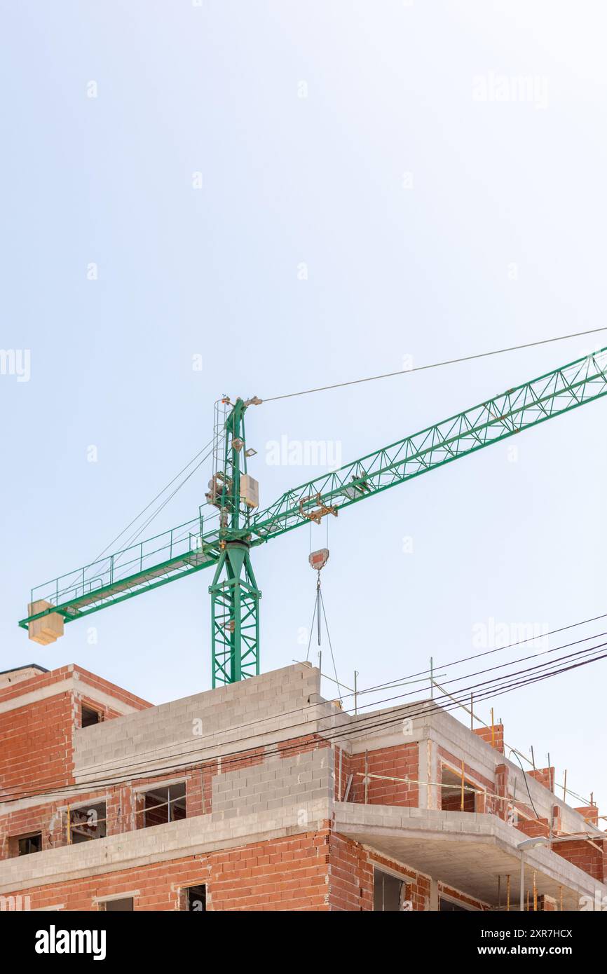 Construction site, featuring a towering green crane and partially ...