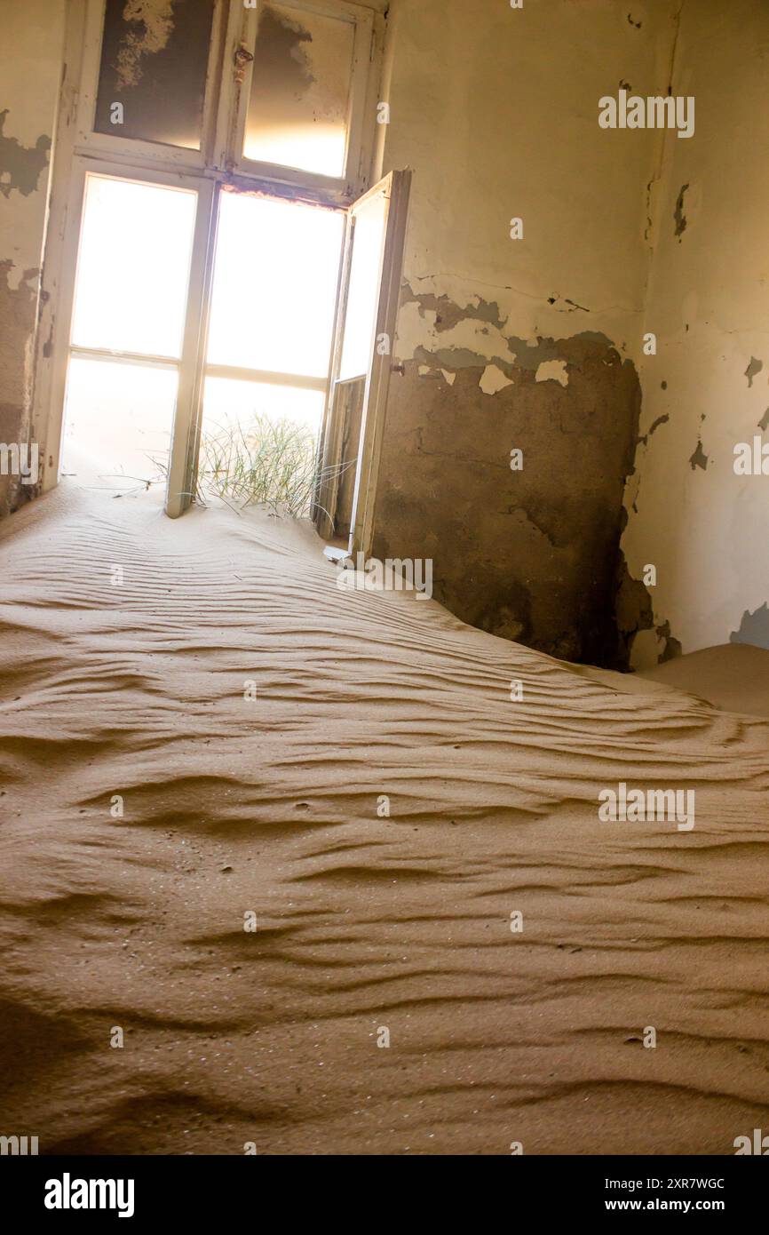 Sand flowing in through an open window into a room in the half buried ...