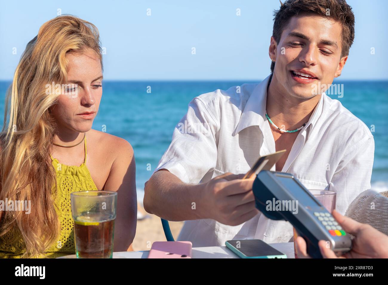 Smiling friends customer paying with contactless credit card in a ...
