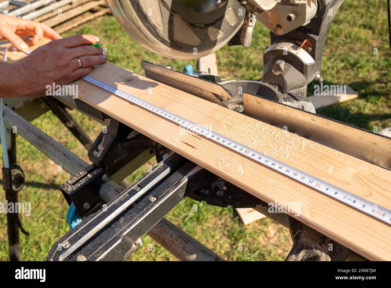 man measuring and cutting a wooden plank with a table saw (bench saw ...