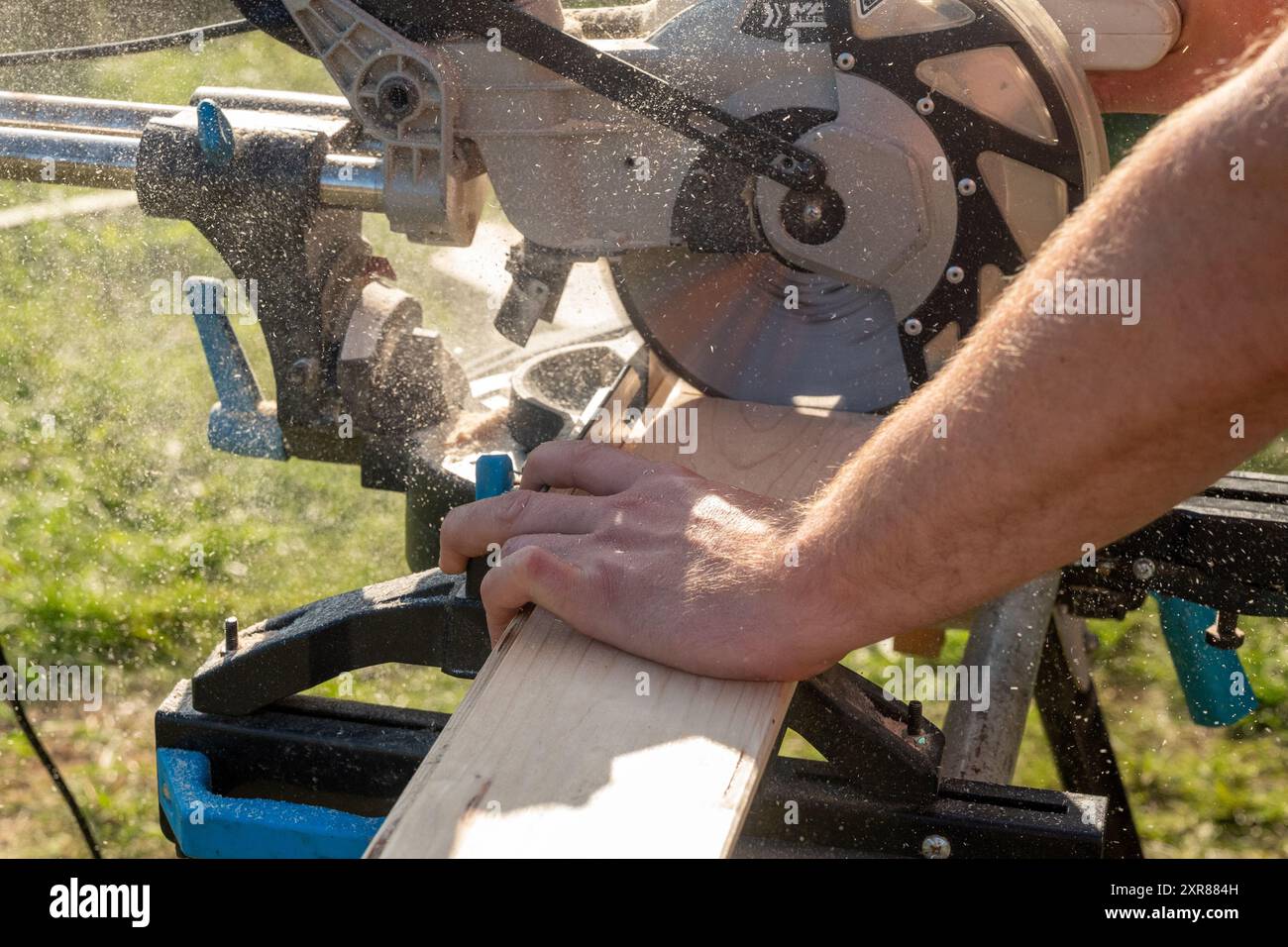 man cutting a wooden plank with a table saw (bench saw) to make a diy ...