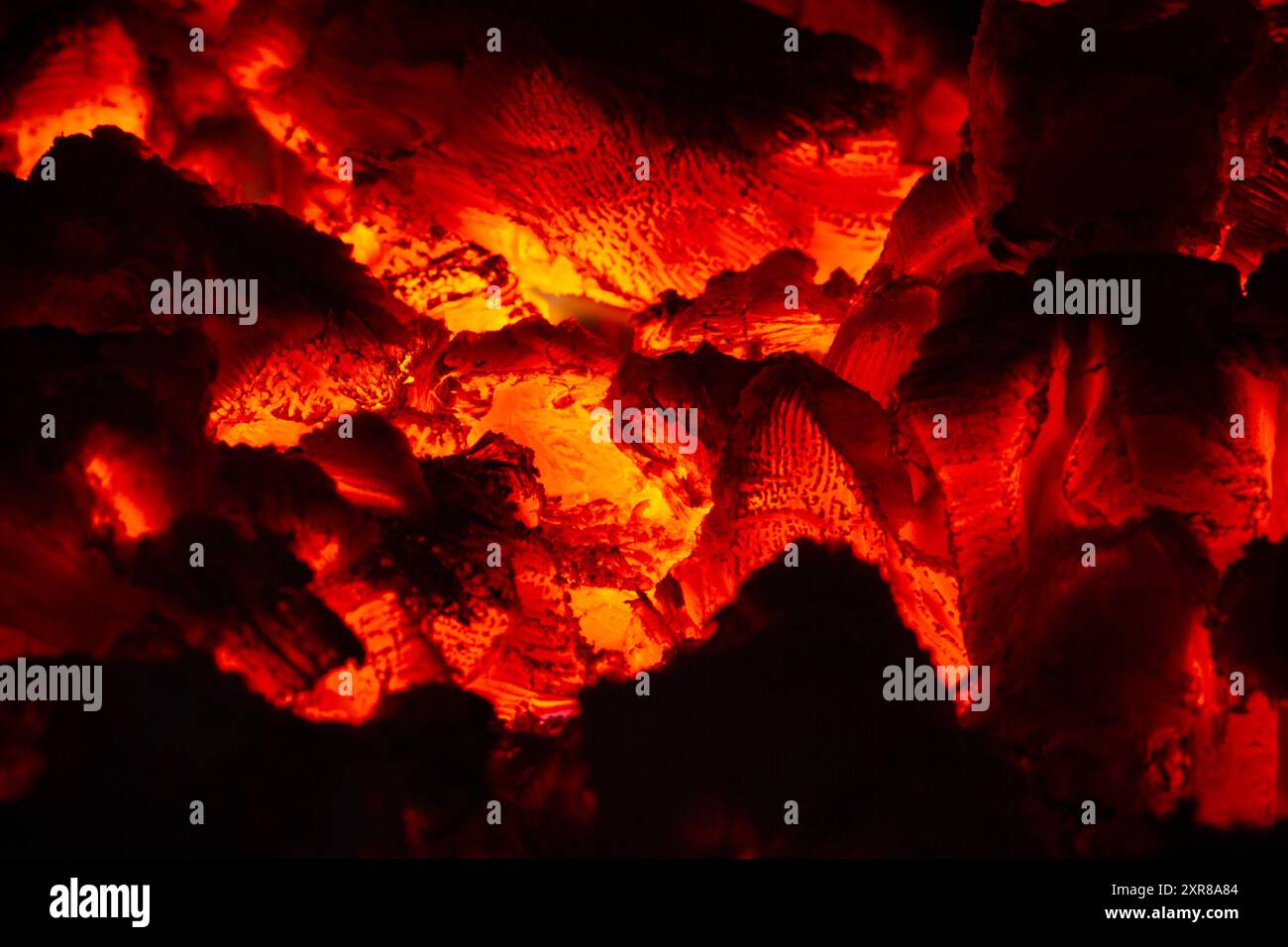 A scattering of burning coals glows brightly in the dark of the stove ...