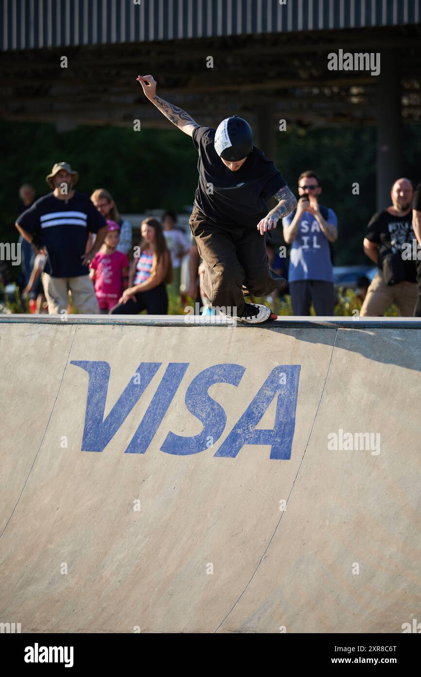 Rollerblader performing a trick on a coping rail in concrete skate pool ...