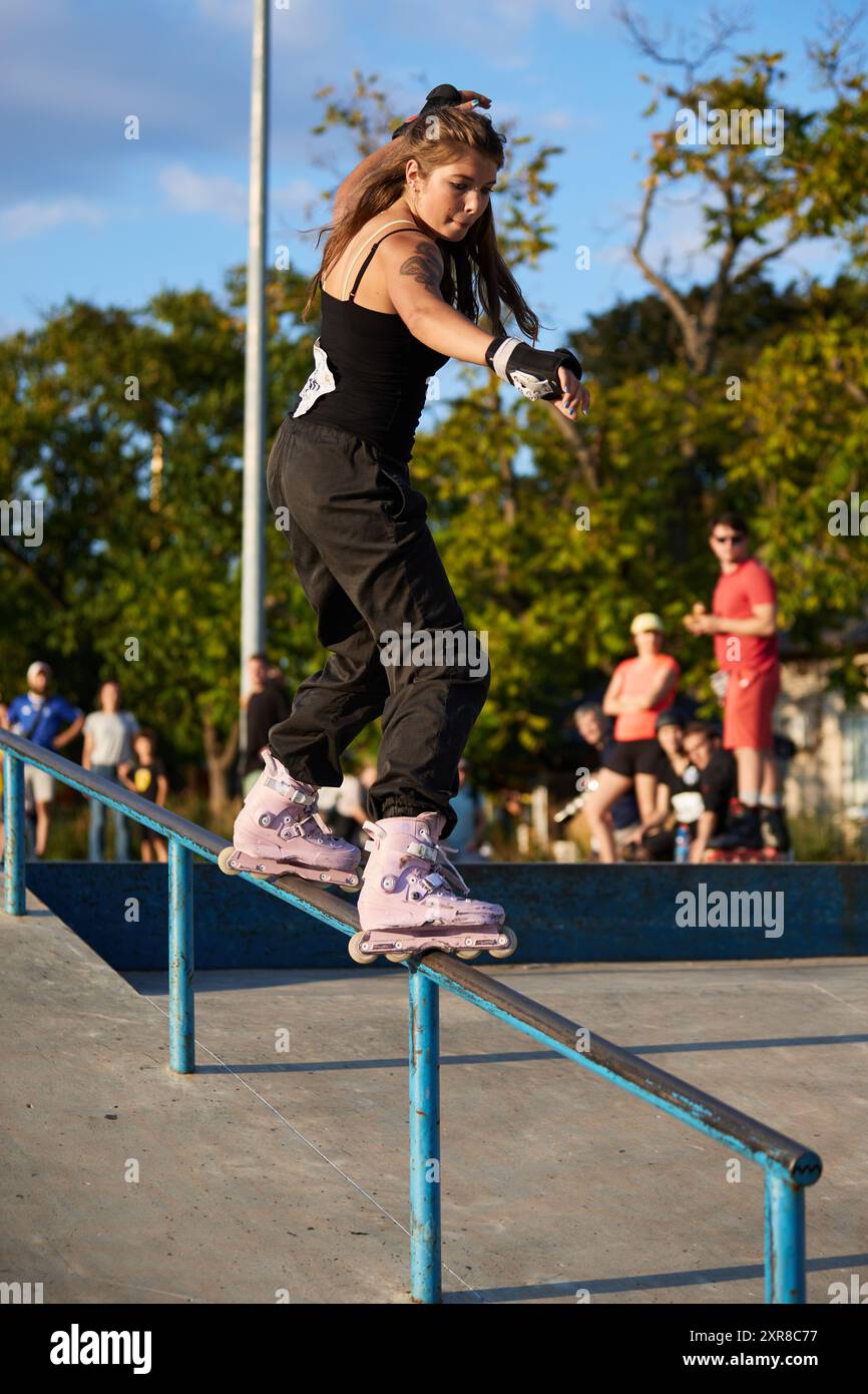 Roller girl grinding on a handrail in skate park. Frontside grind trick ...