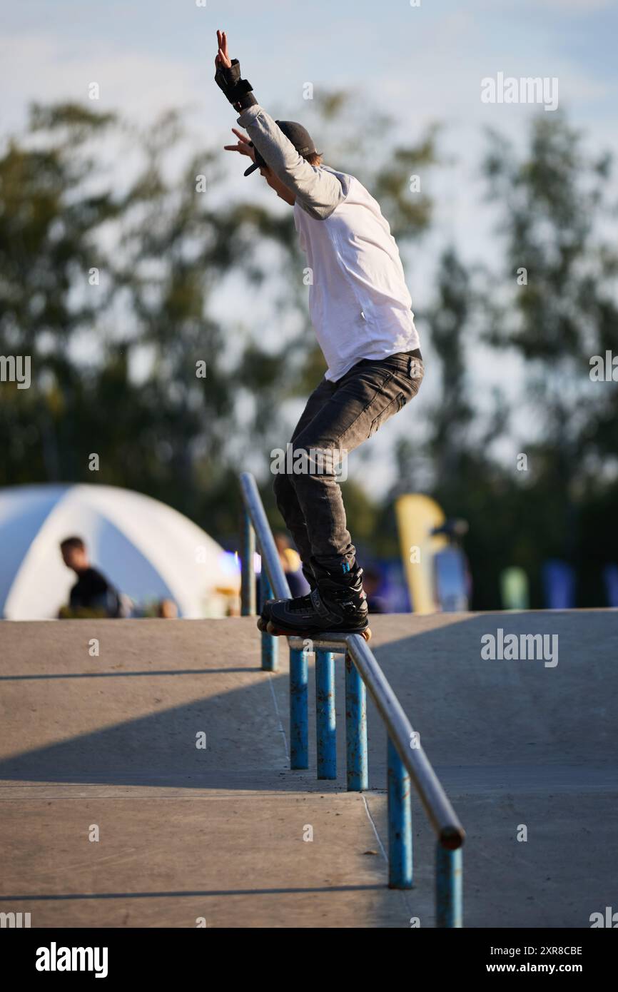 Roller performing royale grind up the kink rail in a skatepark. Extreme ...