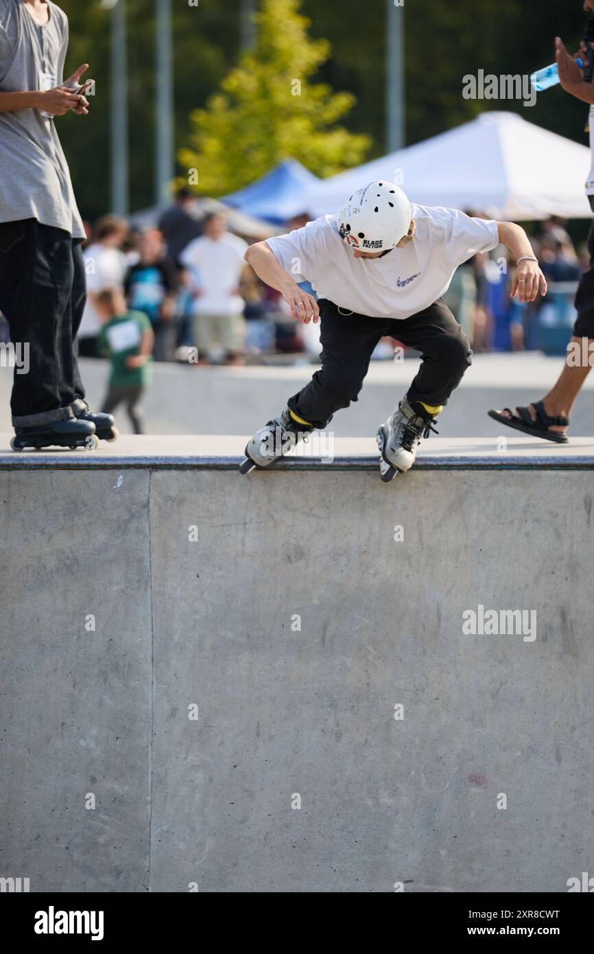 Aggressive roller blader performing bs royale grind in a concrete pool ...