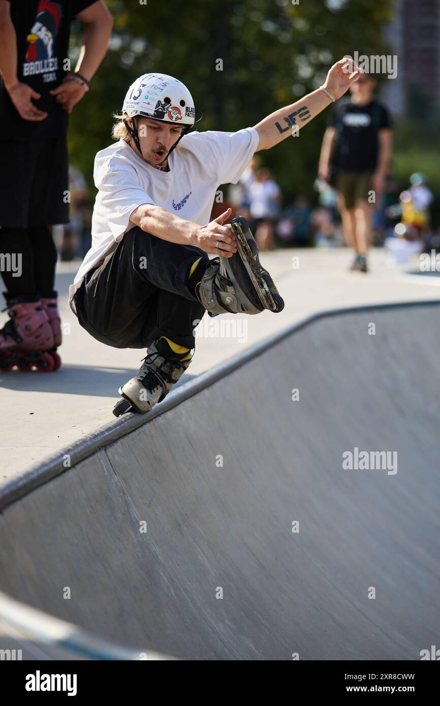 Fishbrain grind in a skatepark. Inline roller blader performing topside ...