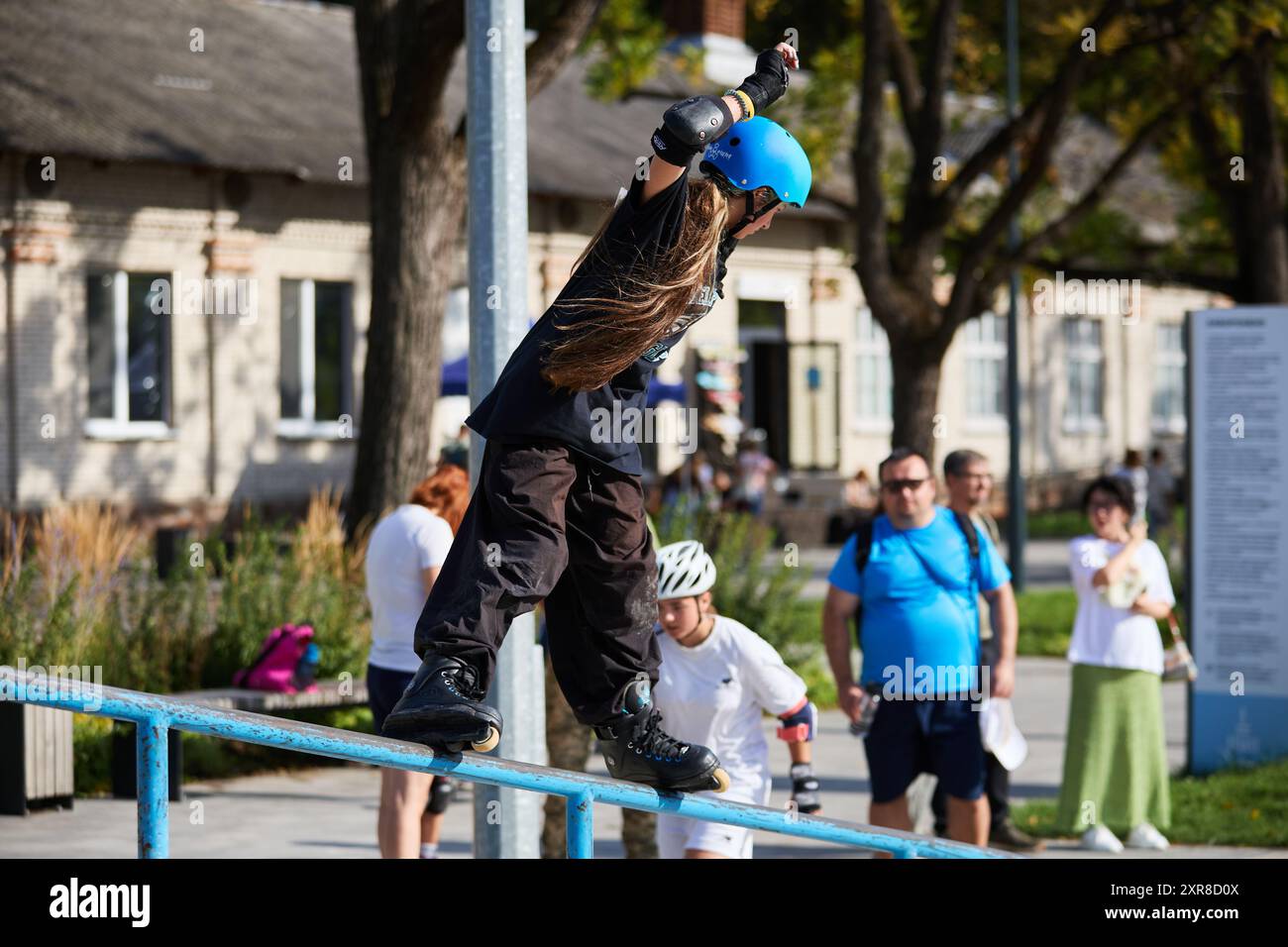 Aggressive roller girl grinding on a rail during skate contest in a ...