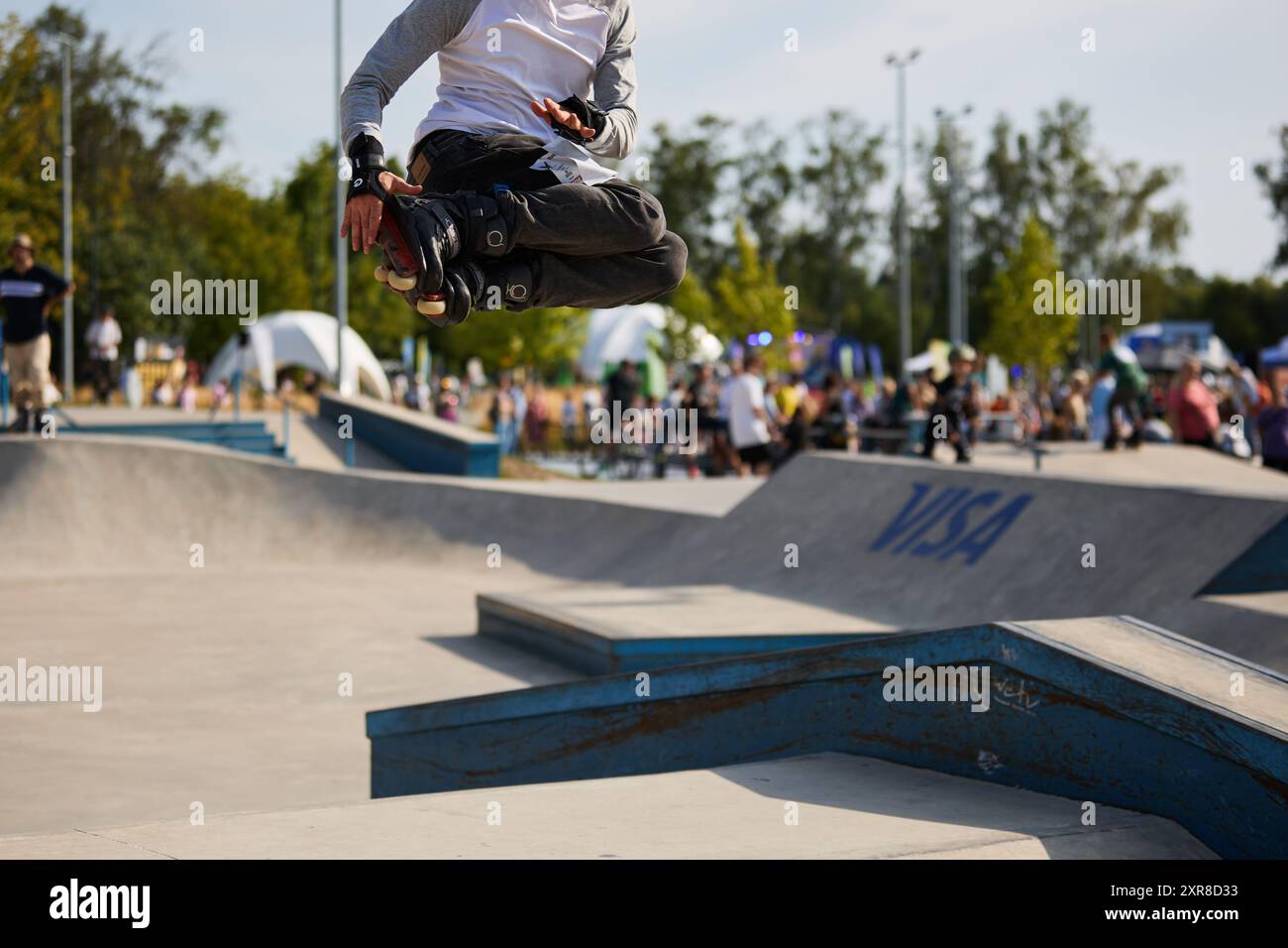 Aggressive in-line skater jumps on ramp in skatepark. Roller blader ...