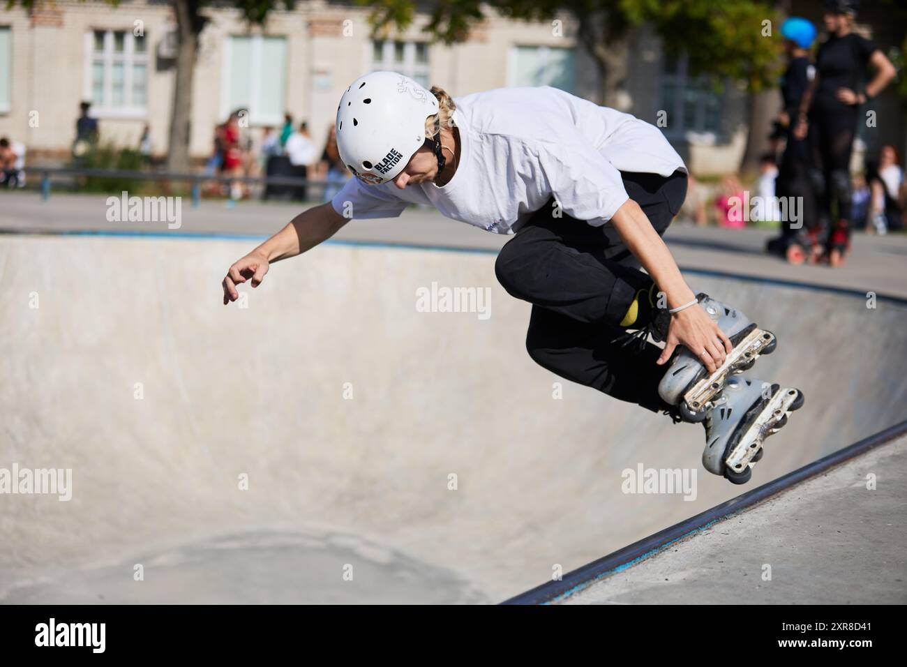 In-line skater doing trick in a skatepark. Roller blader performing a ...