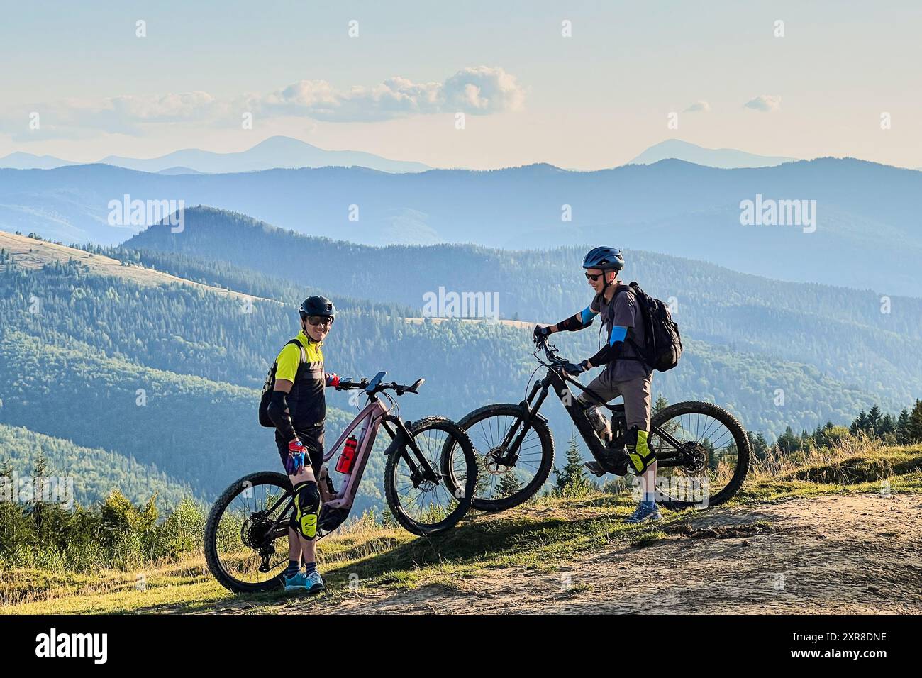 Two cyclists men riding electric bikes outdoors. Smiling male tourists ...