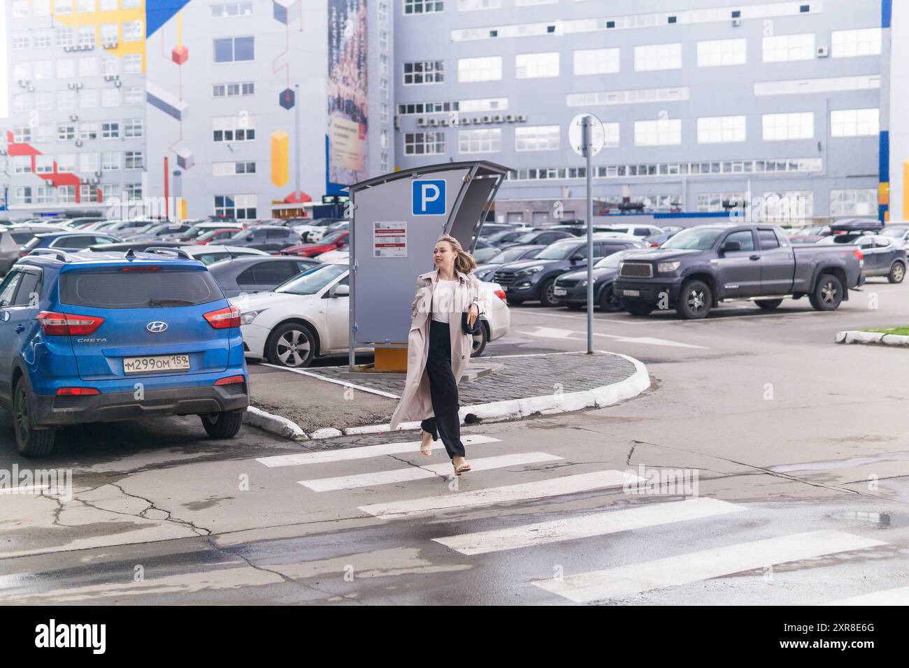 Perm, Russia - July 24, 2024: young beautiful blonde runs across the road in a large parking lot ...
