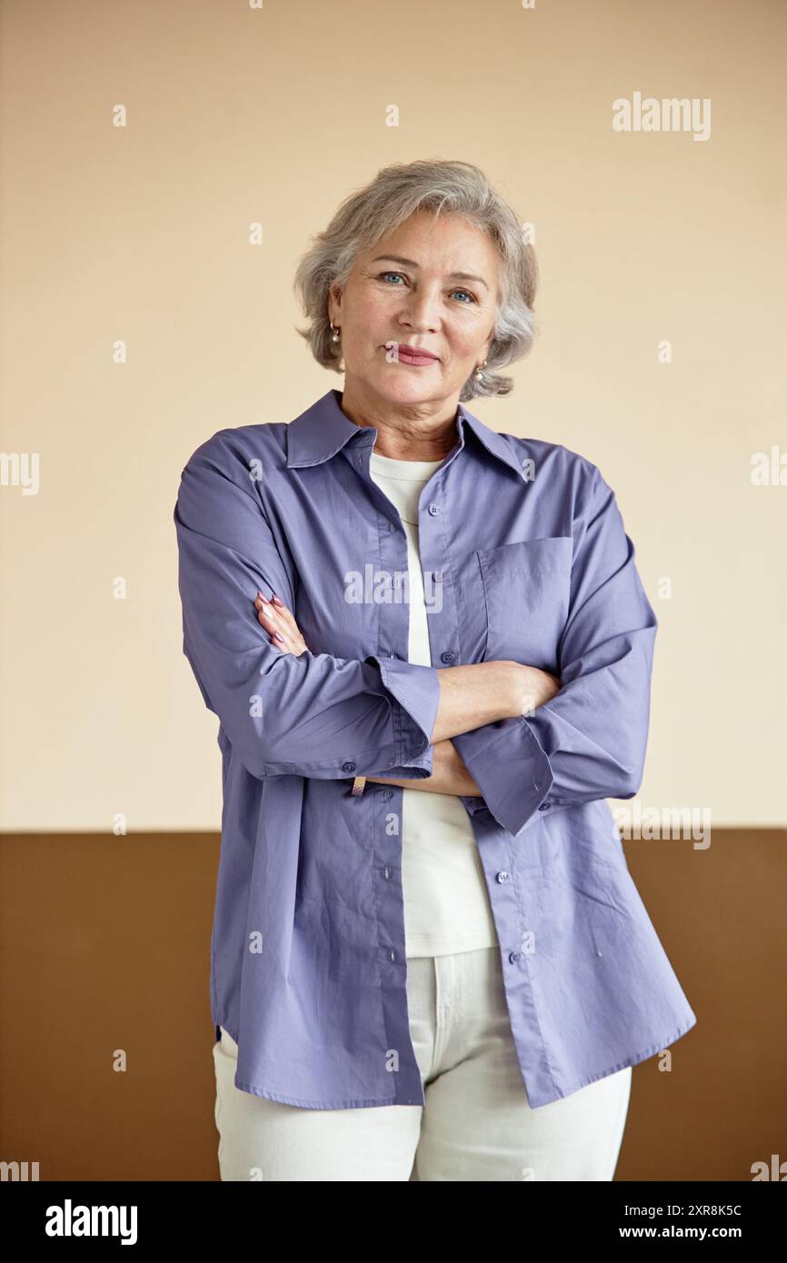 Portrait of senior woman standing with crossed arms and neutral ...