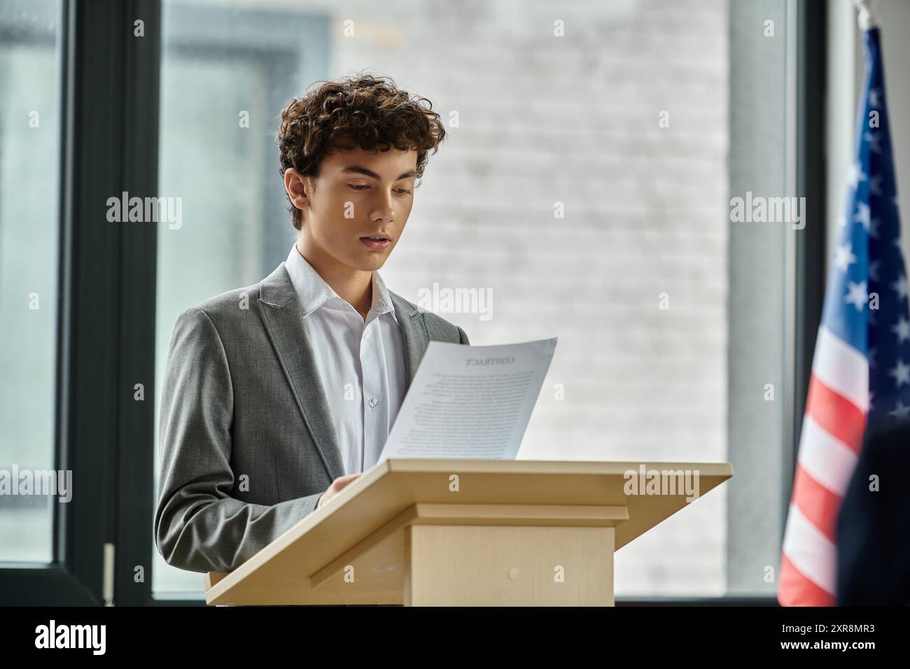 Teenage boy delivers a speech from a podium at a UN Model conference ...