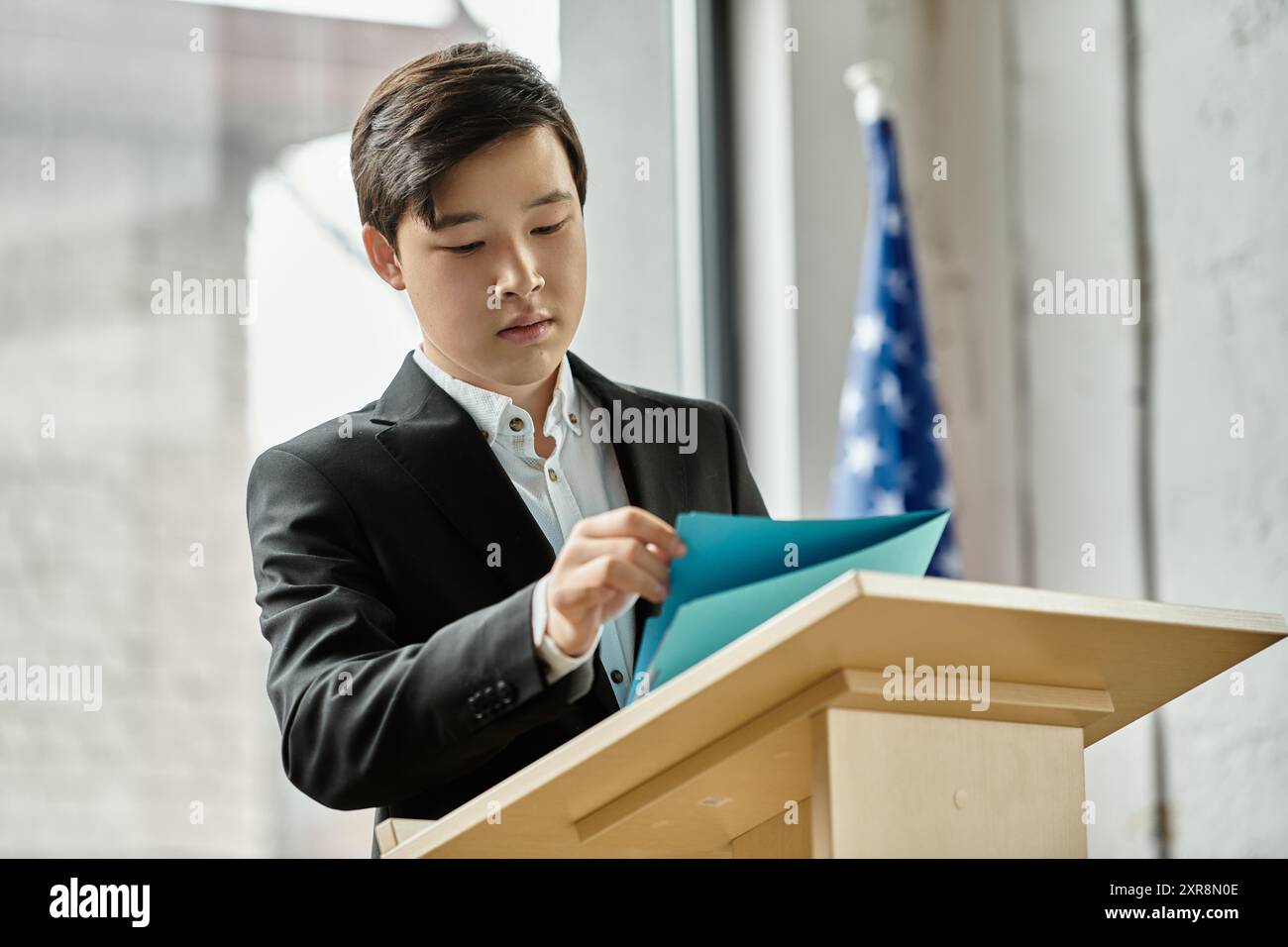 Teenage boy in a suit looks over his notes at a podium Stock Photo - Alamy