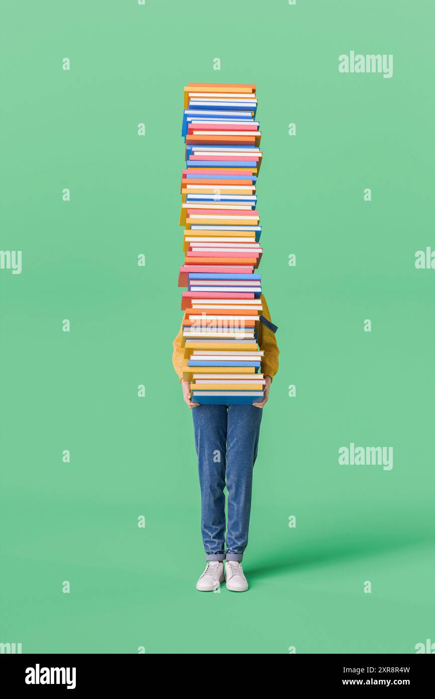 Woman in yellow sweater and blue overalls holding a tall stack of books ...