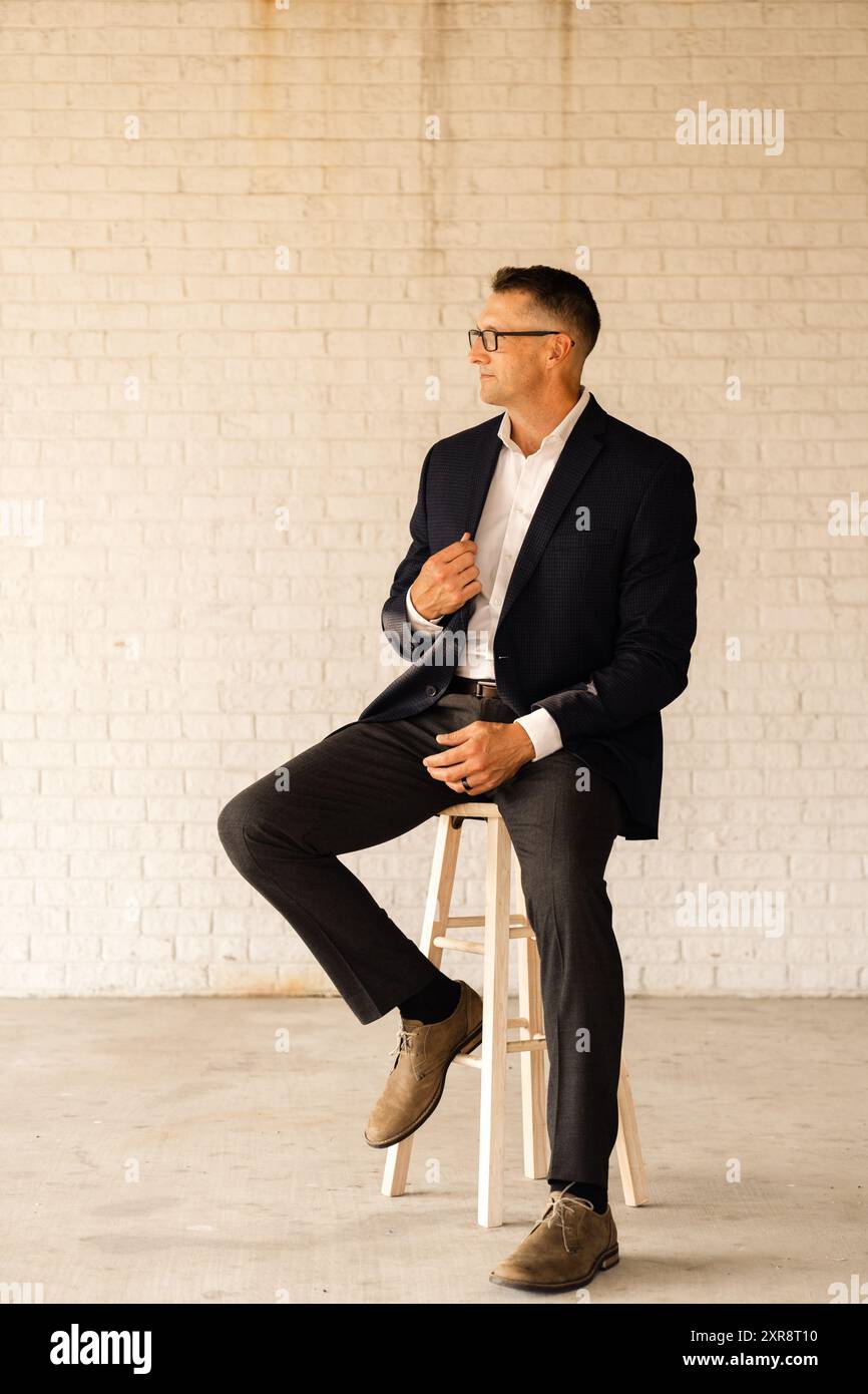 business man sitting on stool looking to the side Stock Photo - Alamy