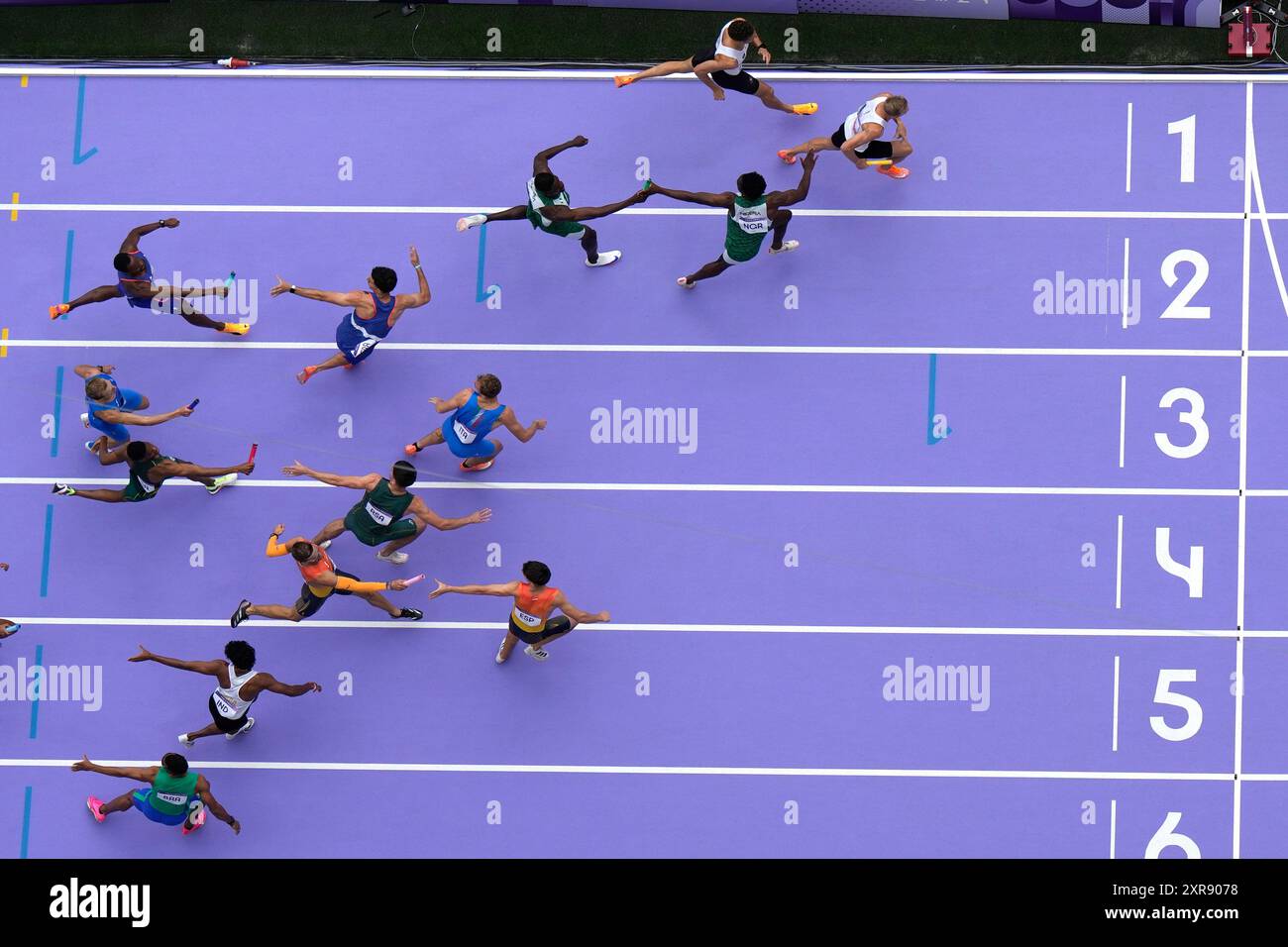 Athletes exchange the baton during a men's 4x400-meter relay heat at ...