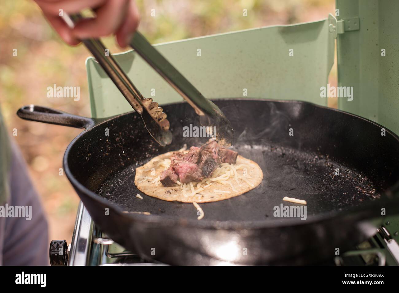 Frying a steak tortilla on a cast iron pan outdoors Stock Photo - Alamy